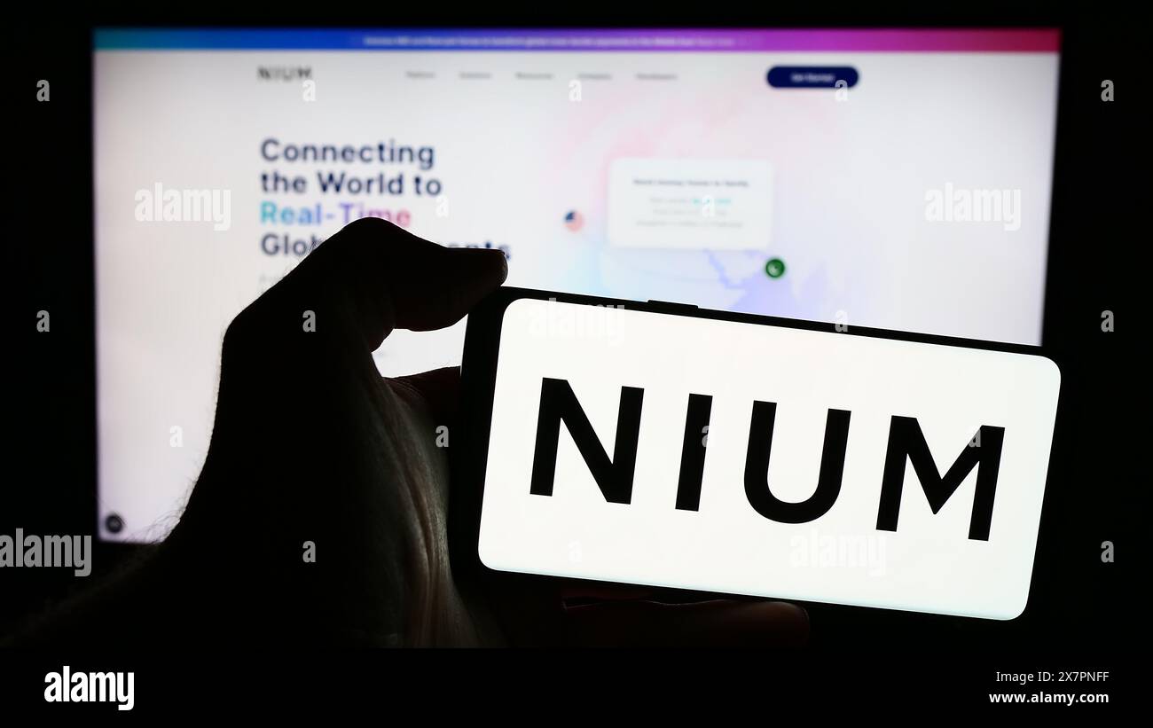 Person holding mobile phone with logo of Singaporean payments company ...