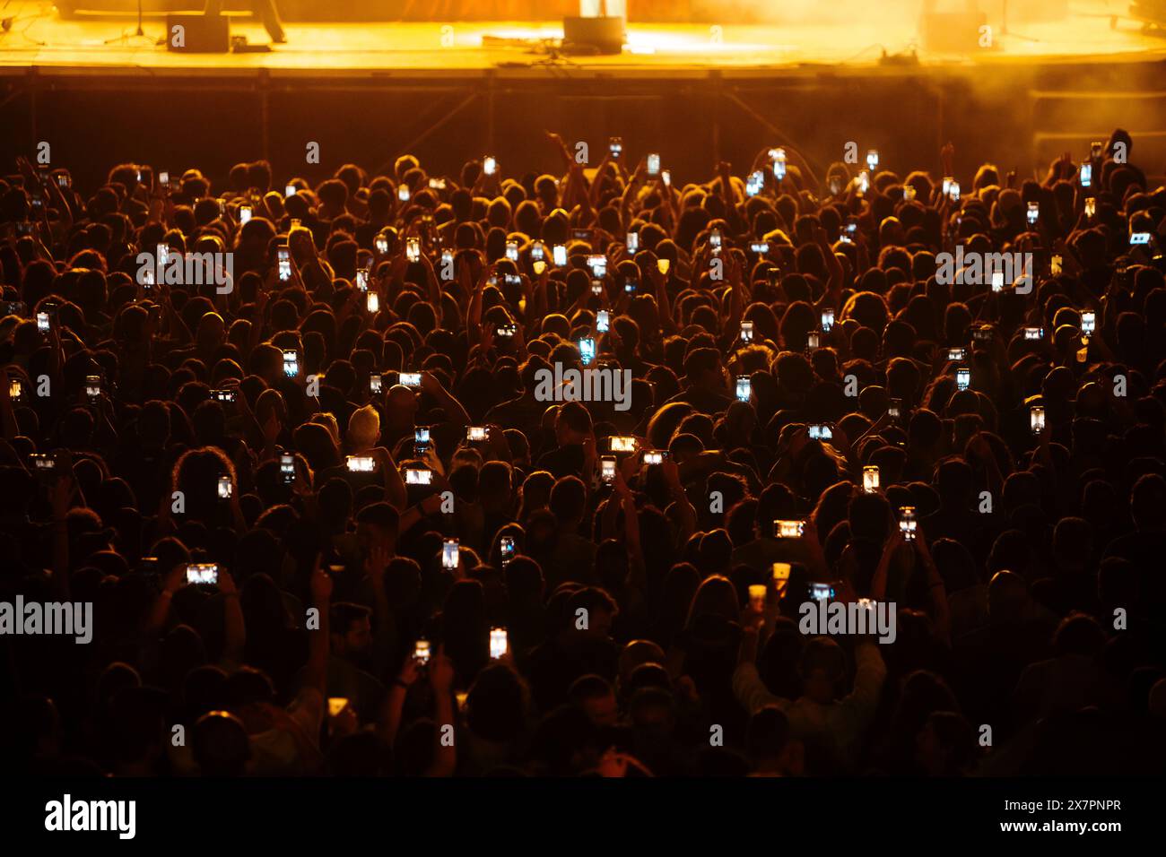 A crowd of people holding up their phones in the air at a concert Stock ...