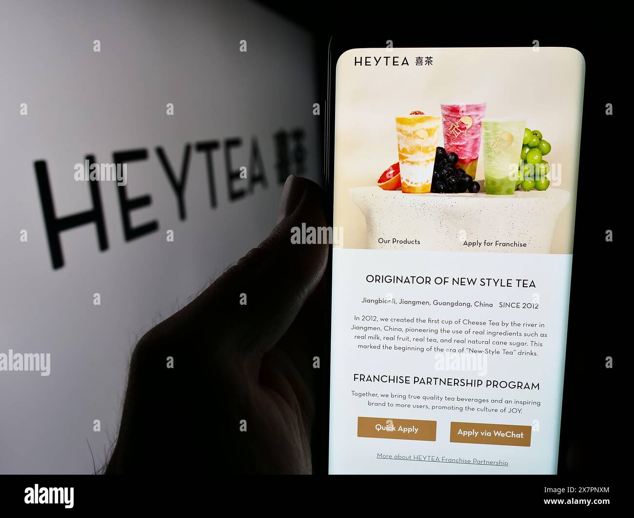 Person holding mobile phone with website of Chinese drink chain company ...