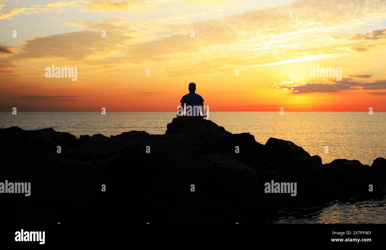 Man meditating in yoga pose on rocks Stock Photo - Alamy