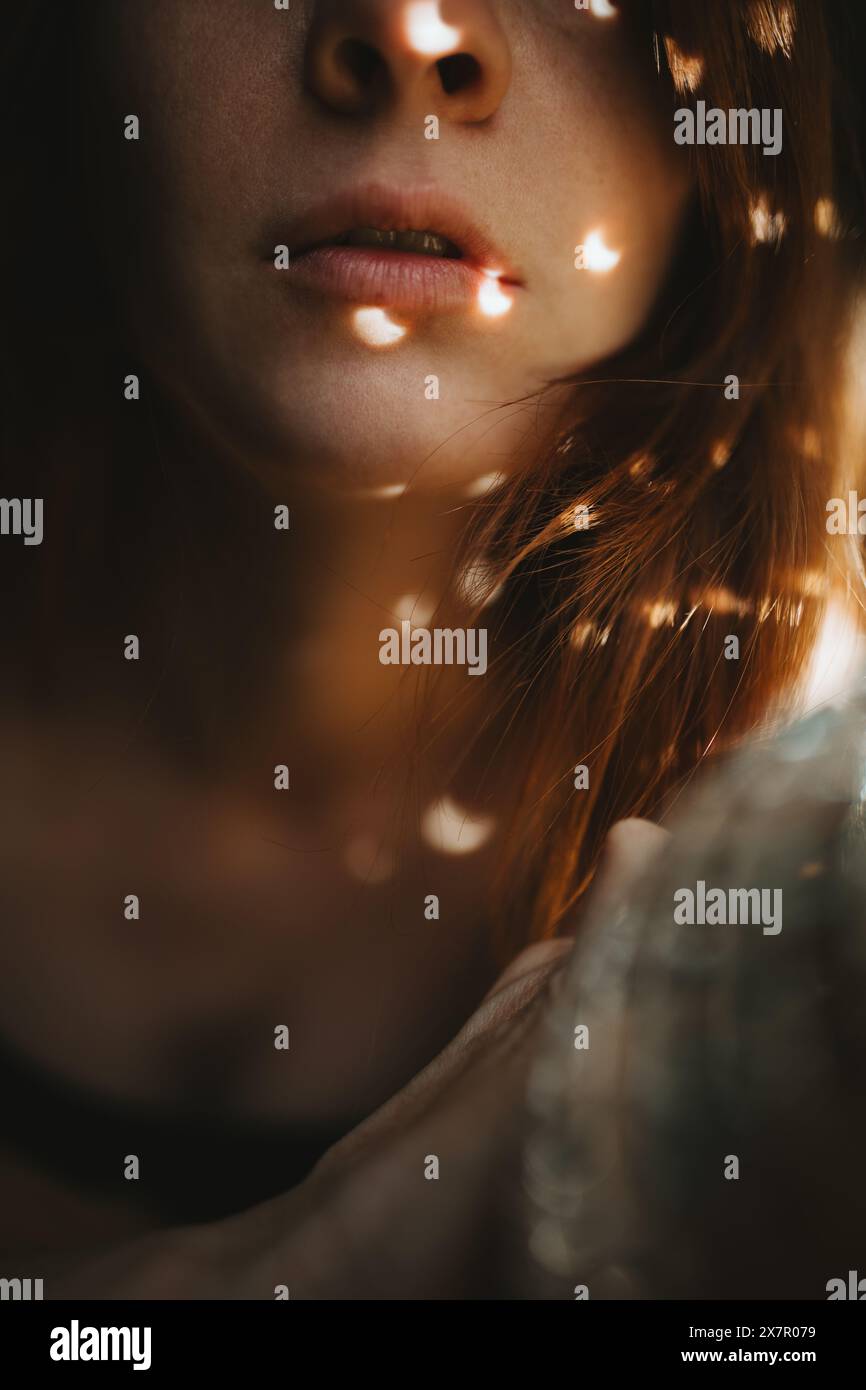 An evocative portrait of a young woman, her face softly lit by dappled ...