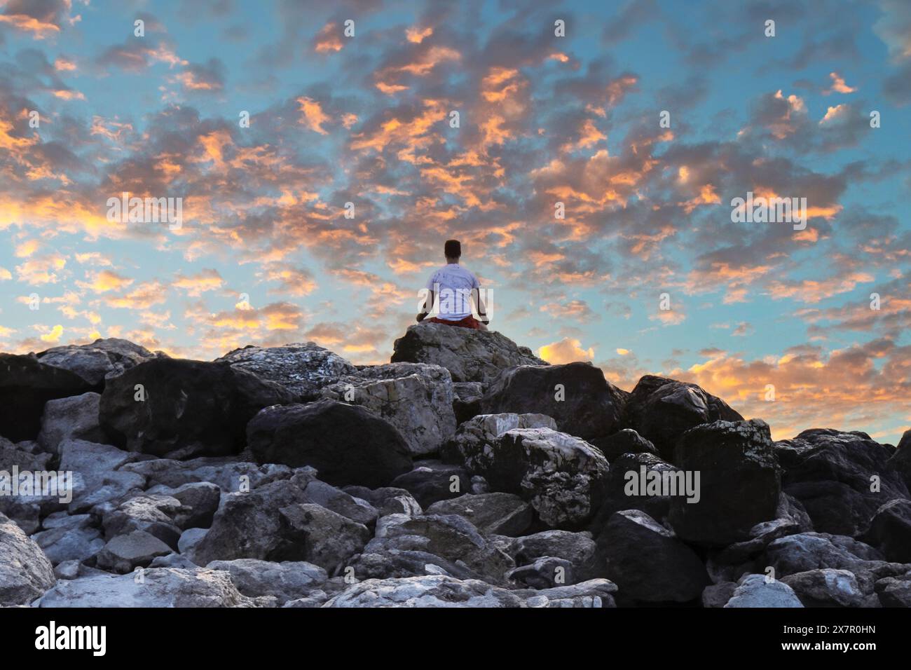 Man meditating in yoga pose on rocks Stock Photo - Alamy