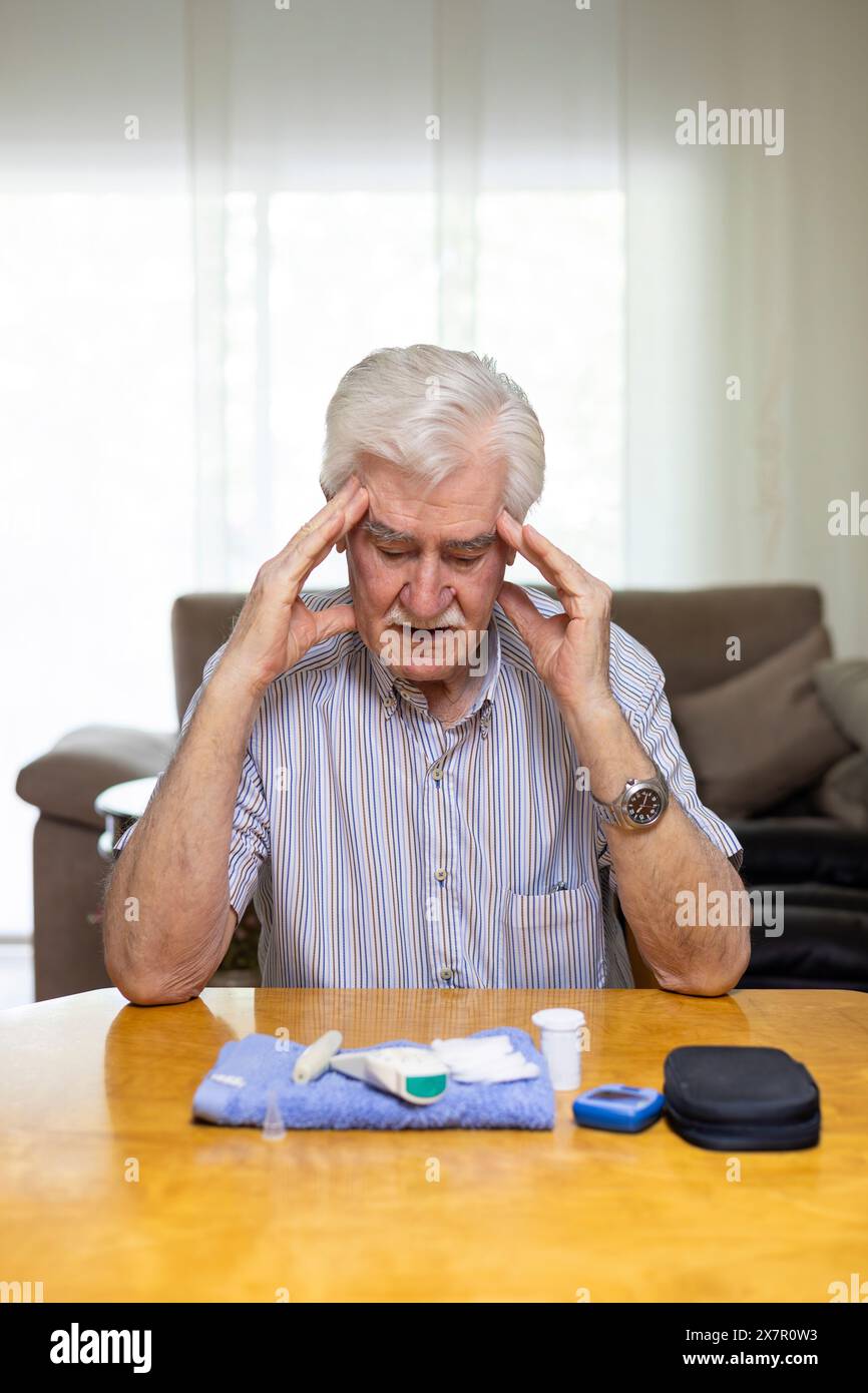 An elderly Caucasian male sits at a table, showing signs of distress ...