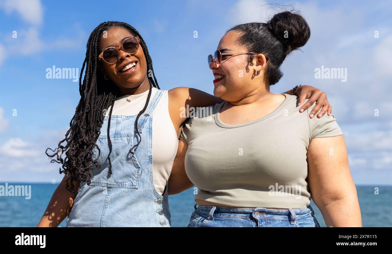 Two happy friends smile and embrace under the sunny Barcelona sky, with ...
