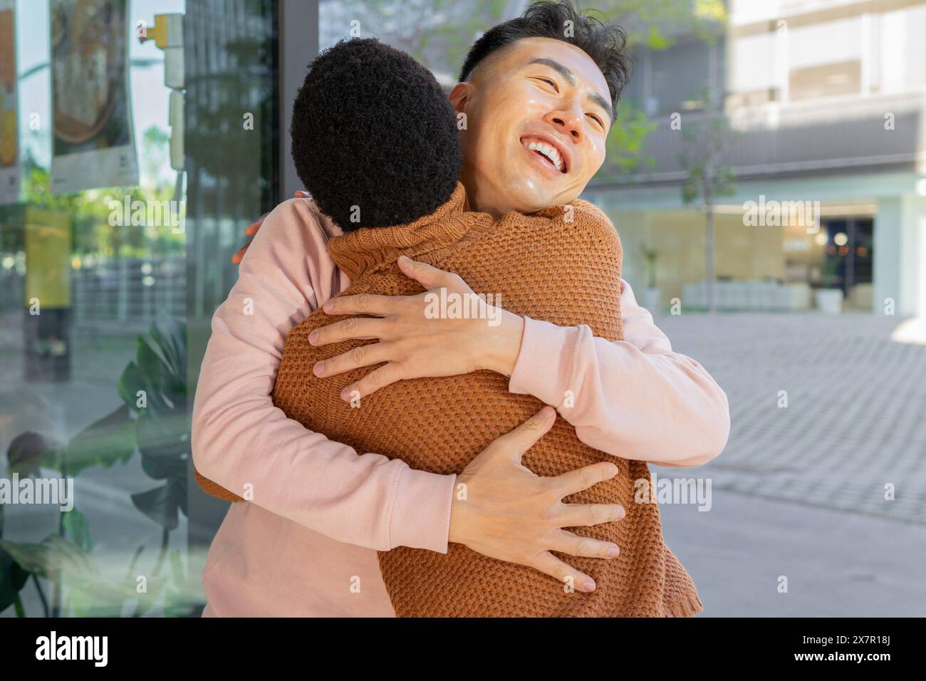 Two multiethnic friends embrace in a heartfelt hug on a sunny day, with ...