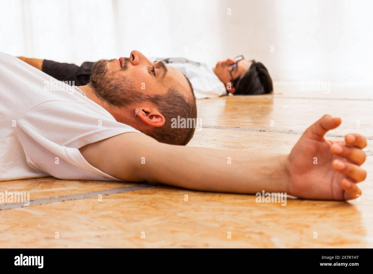 Two individuals lying on the floor, resting after participating in a ...