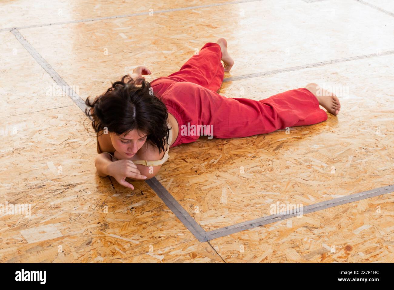 A focused woman in red attire performs a holistic dance, lying on a ...