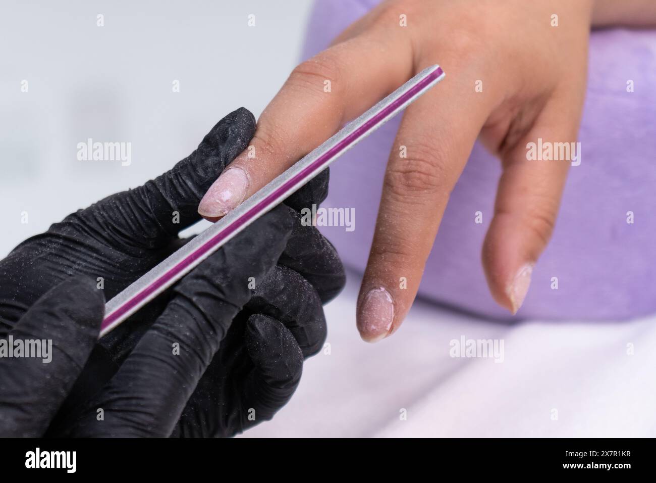 A professional nail technician files a client's nails during a manicure ...