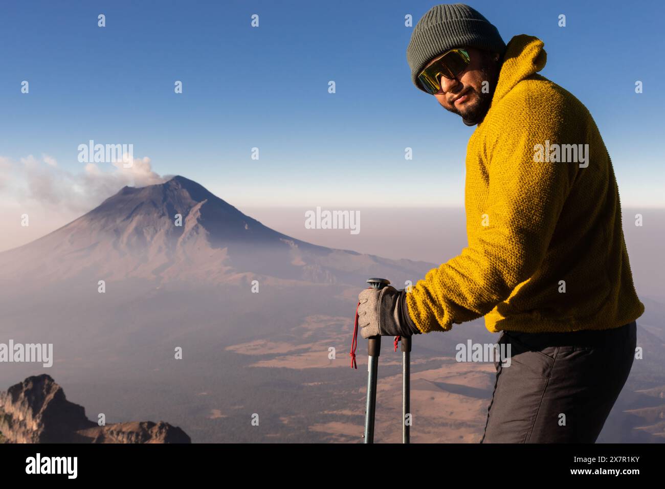 A male hiker in a yellow fleece jacket looks at the distant ...