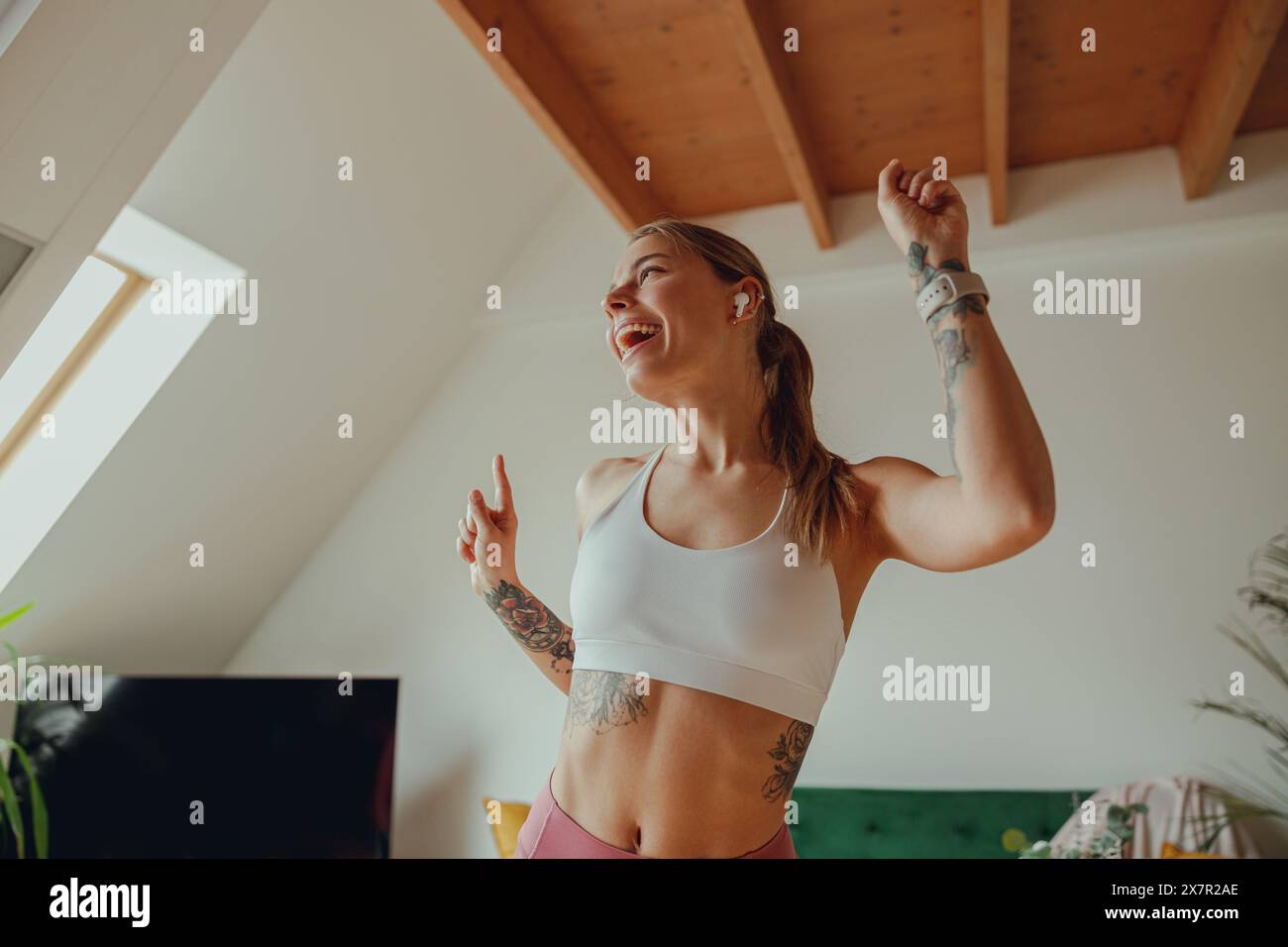 A woman dances in a living room, raising her arms with joy Stock Photo ...