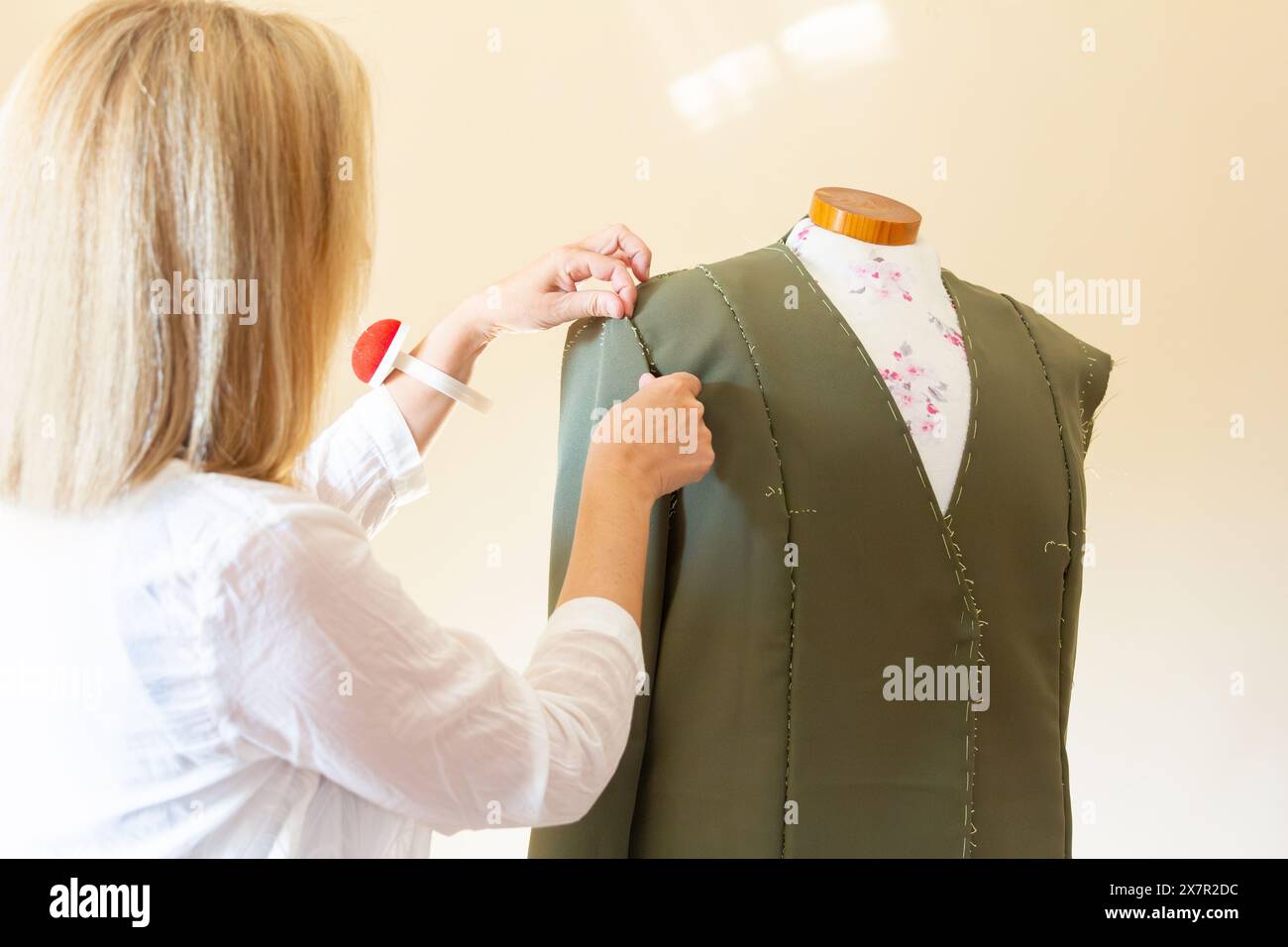 Skilled tailor fitting a garment on a mannequin, marked with basting ...