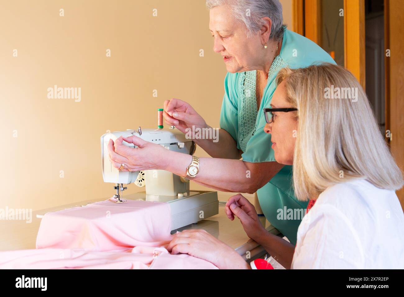 Two women engaged in a sewing project with one teaching the other how ...
