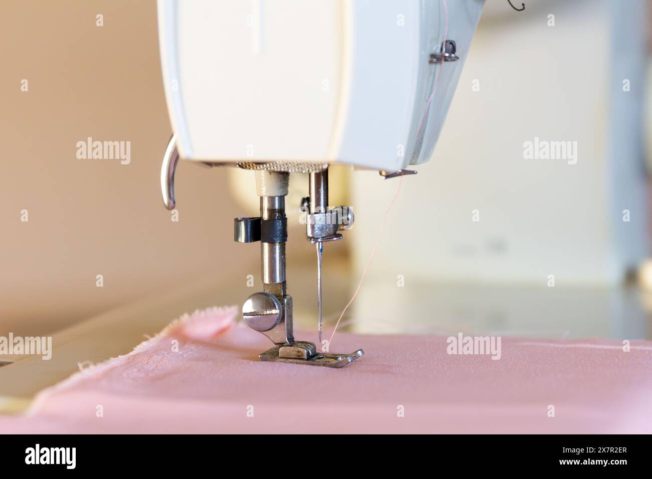 A detailed close-up of a sewing machine's needle and foot with pink ...