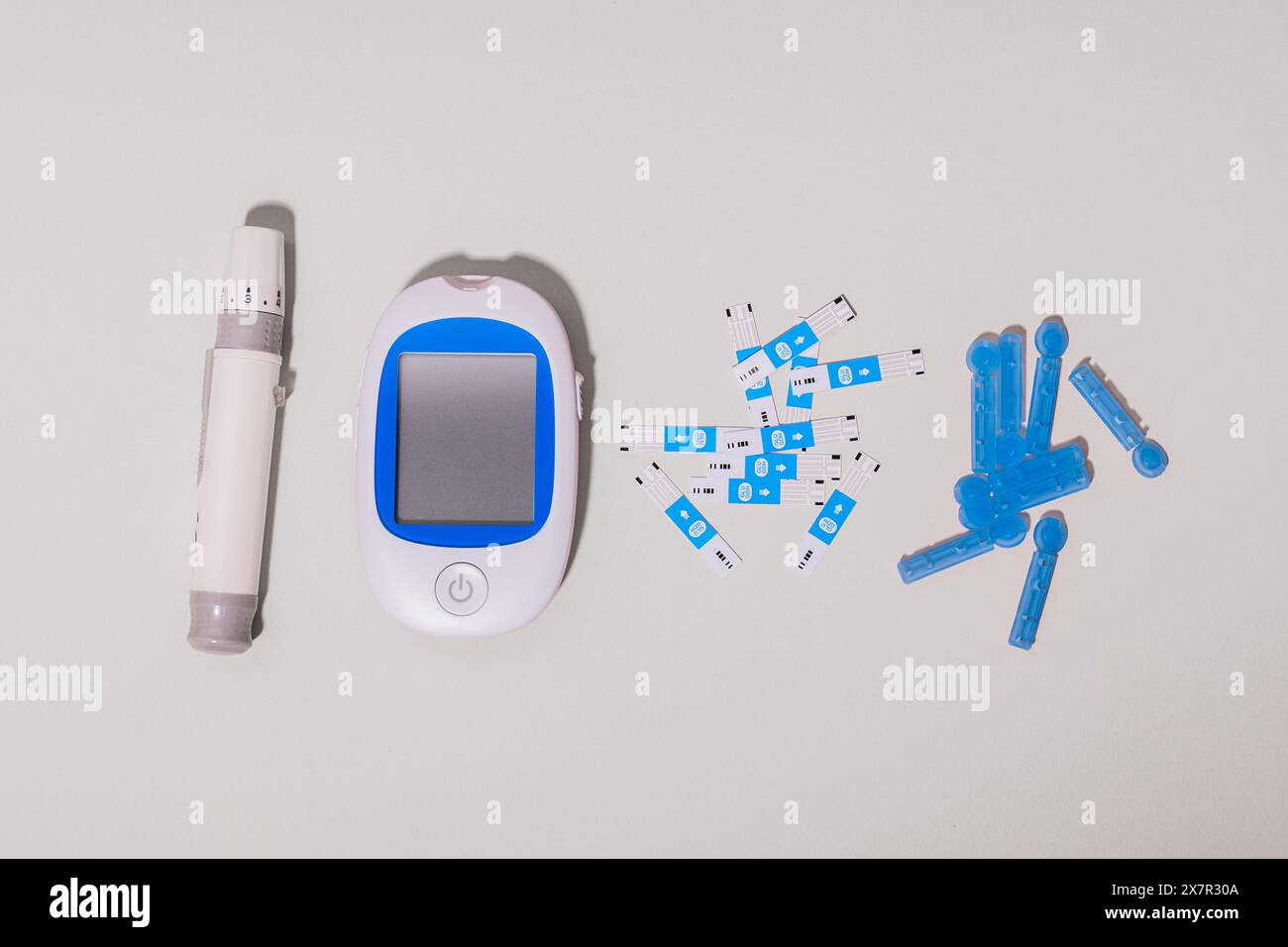 A blood glucose meter, insulin pen, test strips, and lancets laid out ...