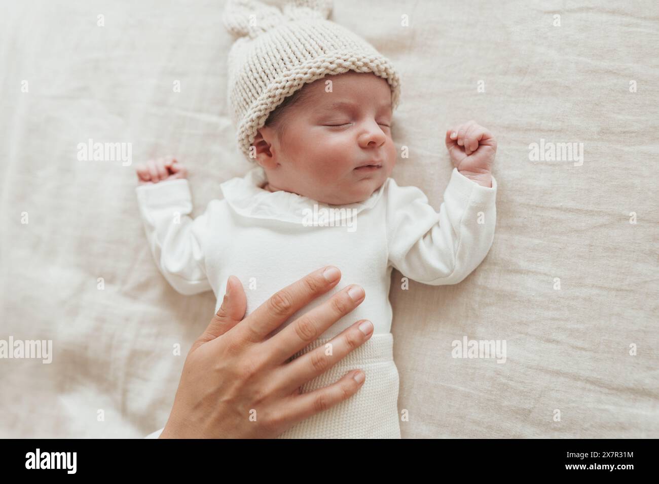 A peaceful newborn baby asleep wearing a knit cap, with a comforting ...