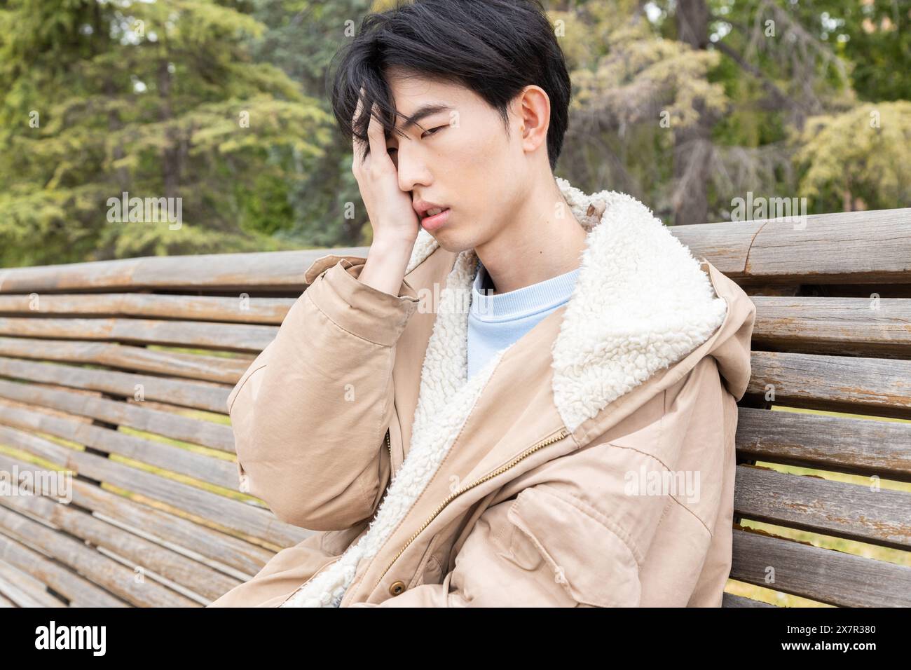 A young Asian man experiences symptoms of hypoglycemia while sitting on ...