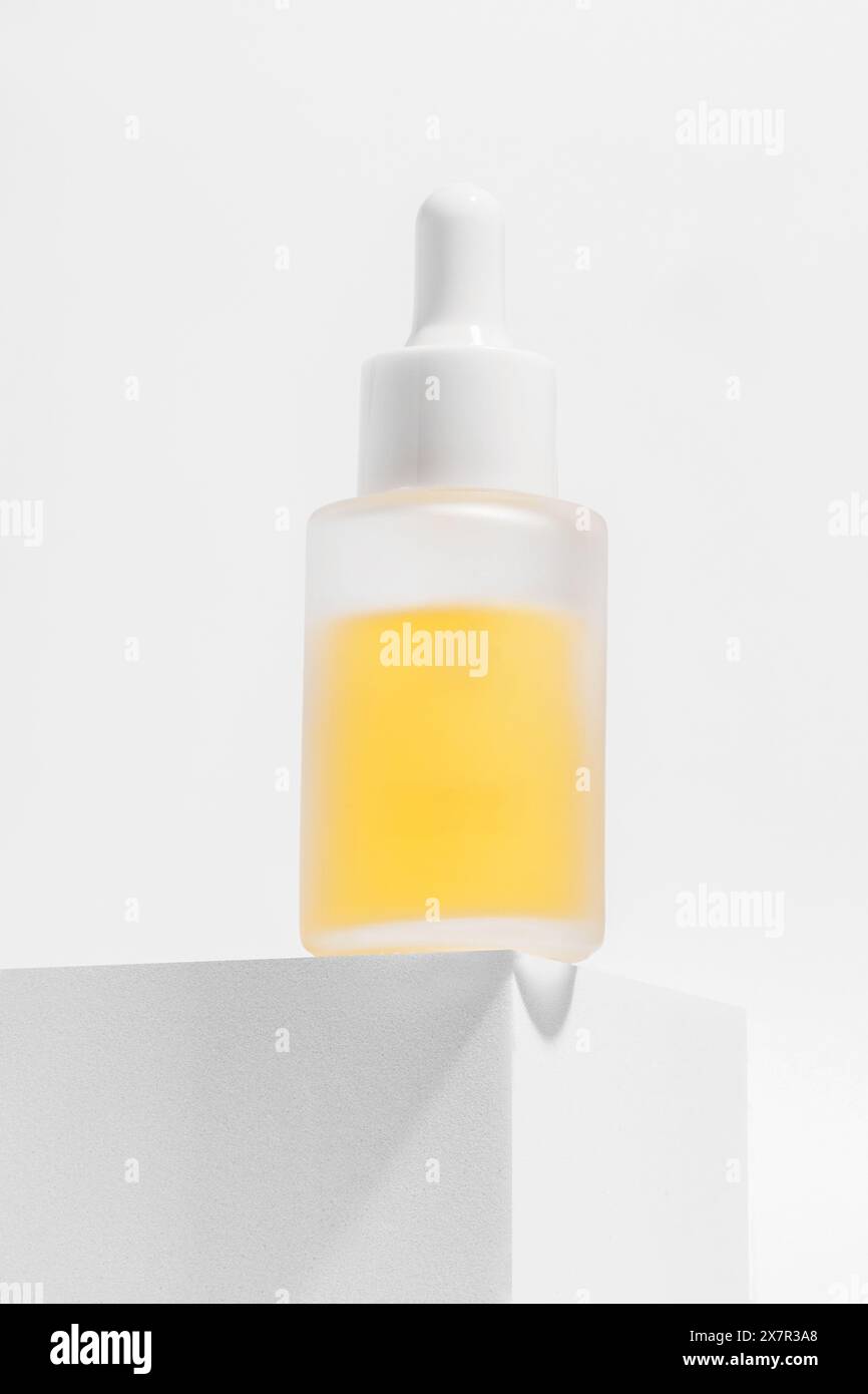 Minimalist image of a cosmetics serum bottle with a bright yellow serum ...