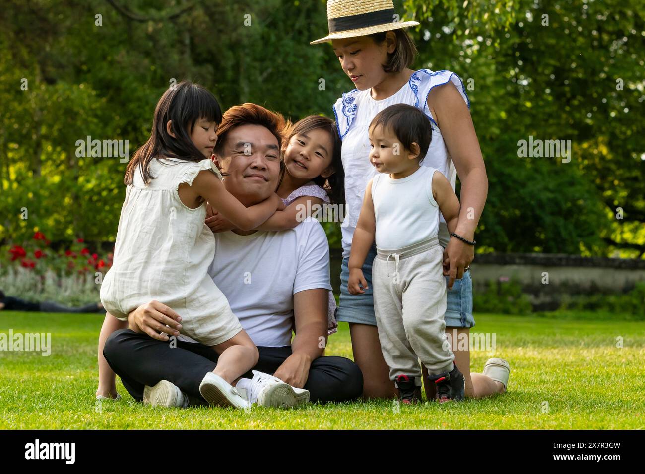 A happy Asian family with three children embracing their father on a ...