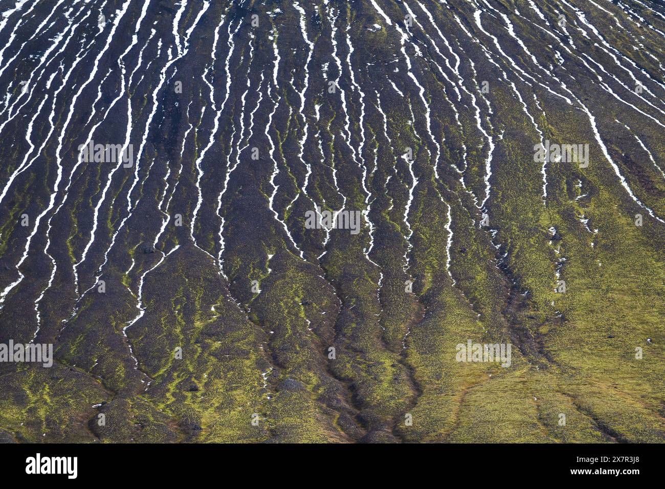 Aerial view of a moss-covered Icelandic hillside with contrasting white ...