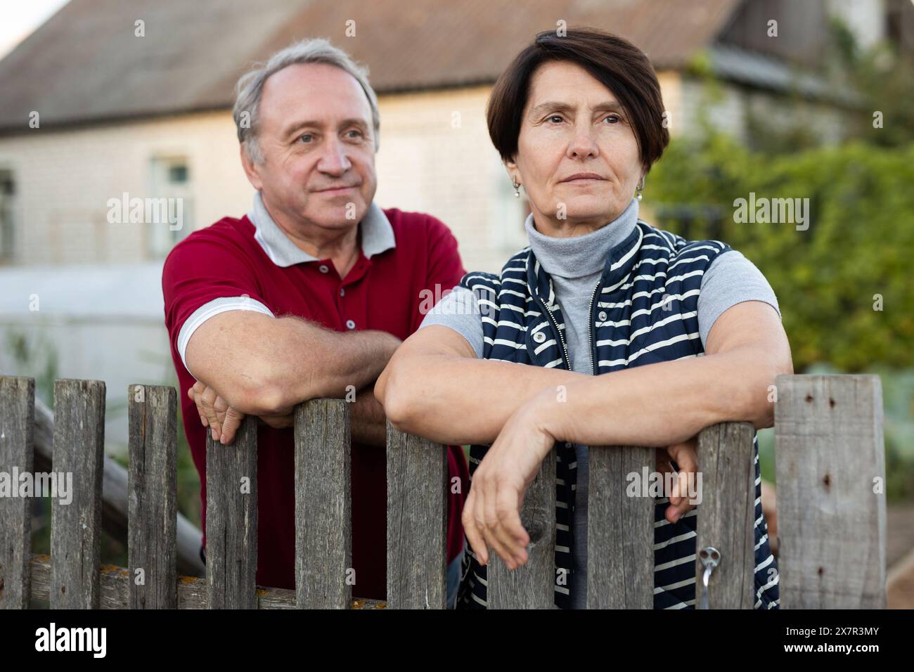 Happy married elderly couple have conversation near the fence of their ...
