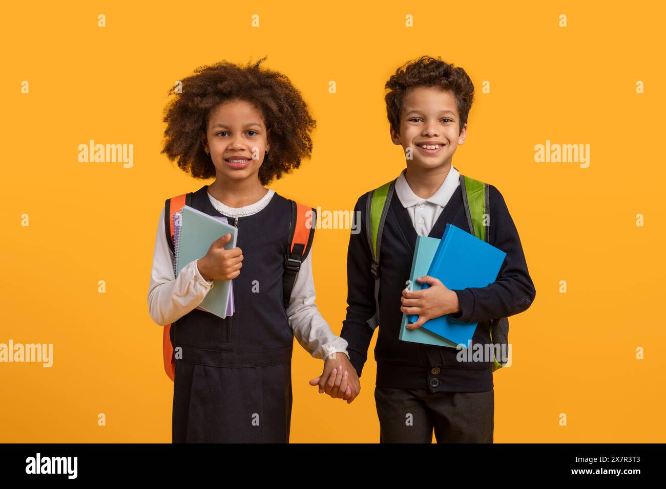 Two School Children Holding Hands in Front of Yellow Background Stock ...