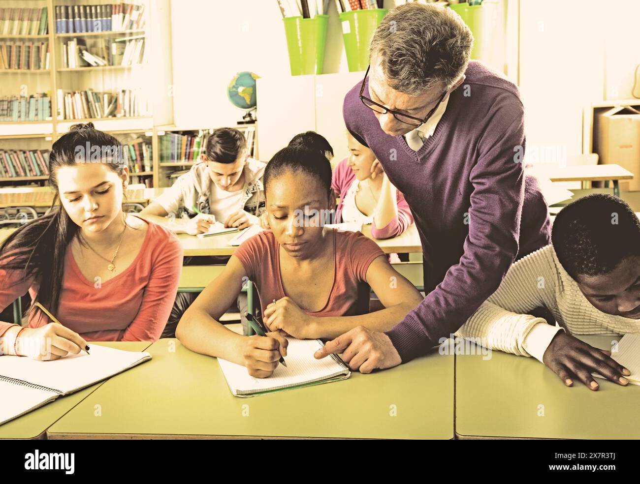 Teacher helping African-American pupil in classroom Stock Photo - Alamy