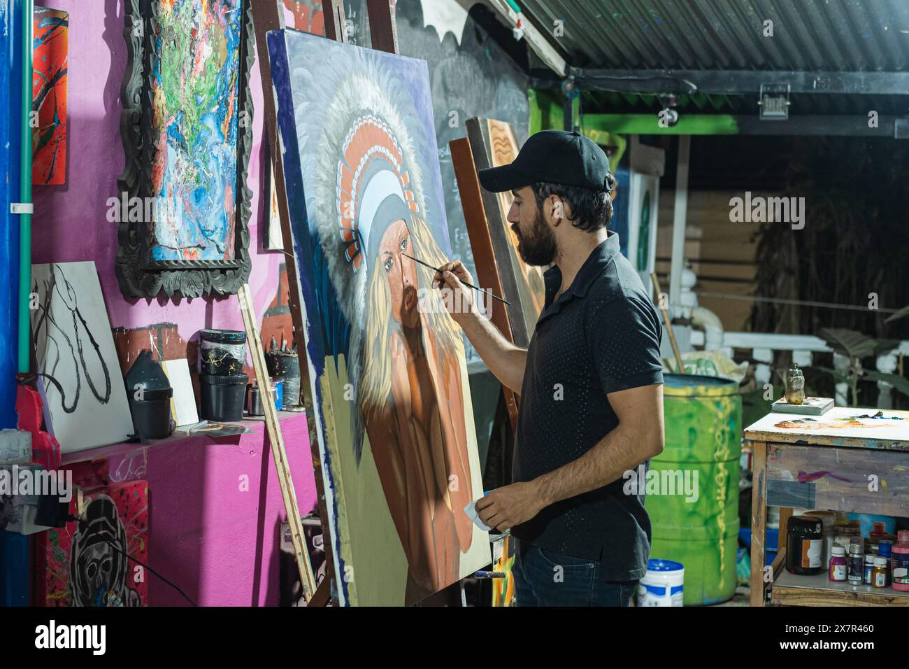 Latin American artist captured from a side view, painting a vibrant ...