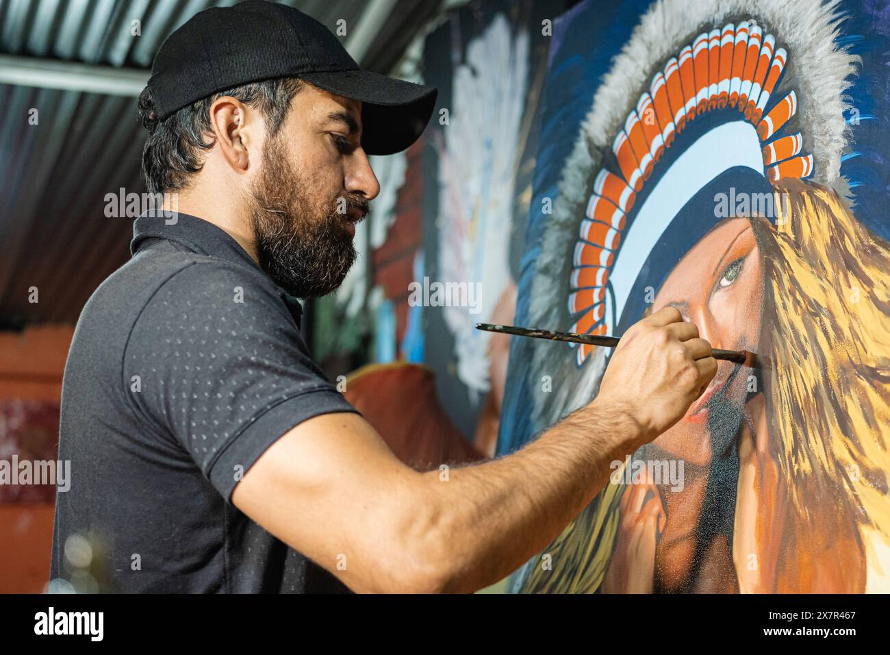 Latin American artist in a side view painting a detailed portrait of a ...