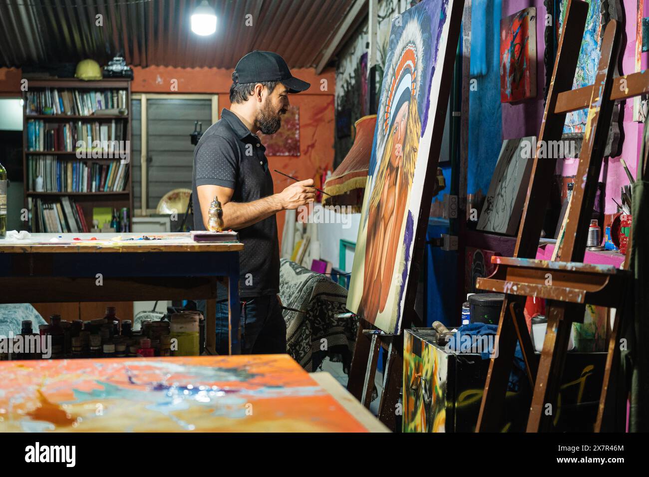 An artist in side view is carefully painting a canvas in his eclectic ...