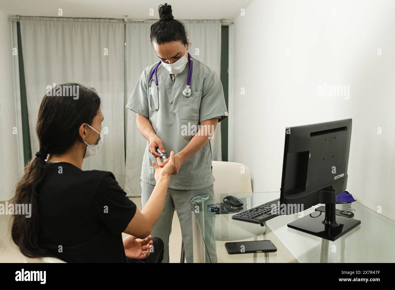 A medical professional issues a glucose meter to a patient to check her ...