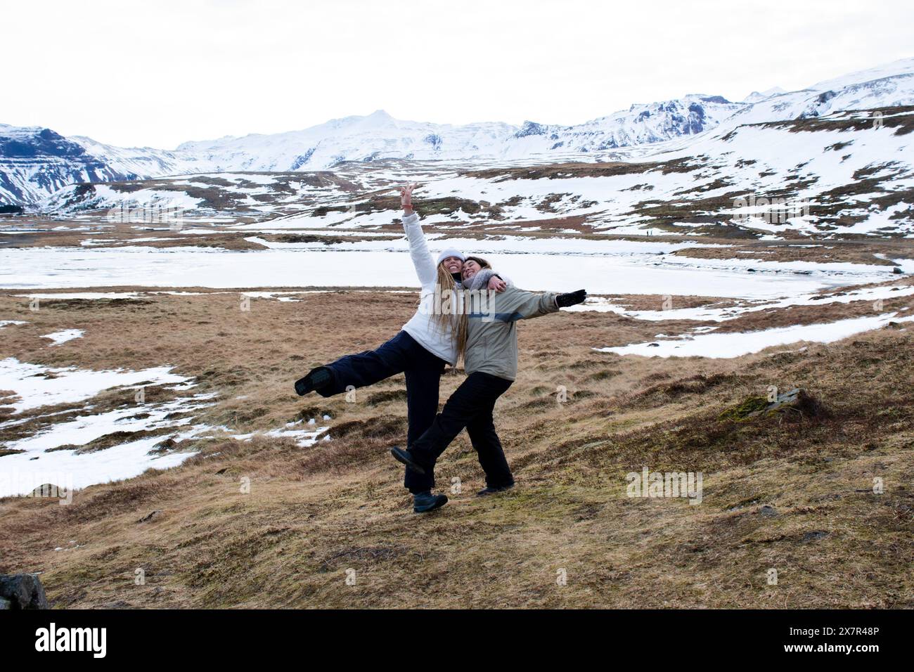 Two joyful people engage in playful poses against a backdrop of a vast ...