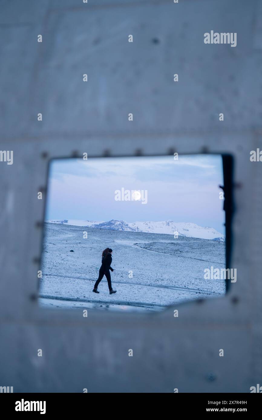A person framed by a squared opening walks across a snowy Icelandic ...