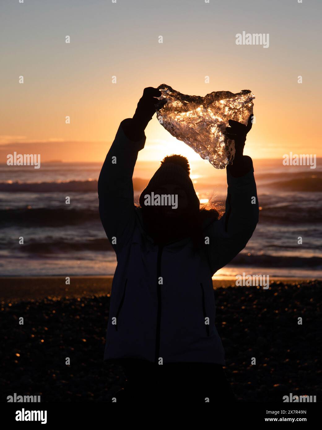 Silhouette of a person holding a large, clear piece of glacial ice ...