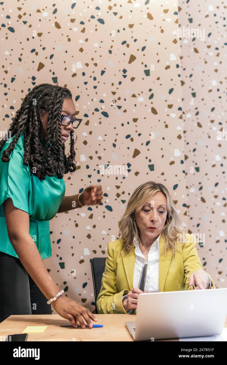 Two businesswomen engage in a collaborative task in a modern coworking ...