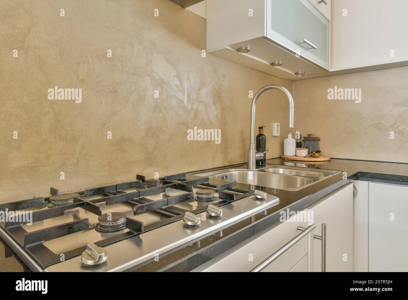 Elegant modern kitchen with a gas stovetop and beige backsplash at ...