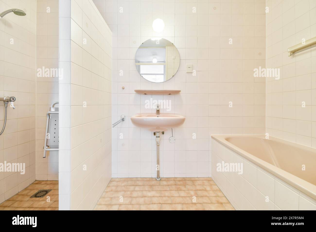 A pristine and well-lit bathroom featuring a wall-mounted sink, circular mirror, tiled walls ...