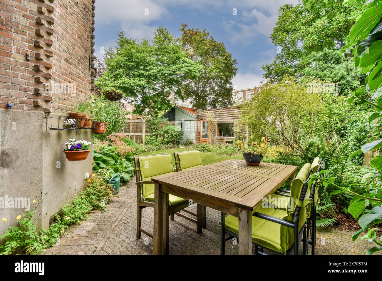 Urban backyard garden featuring a wooden dining table, lush greenery ...