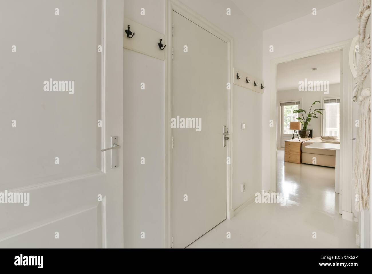 A well-lit hallway with a clean, white aesthetic leads to a warmly ...