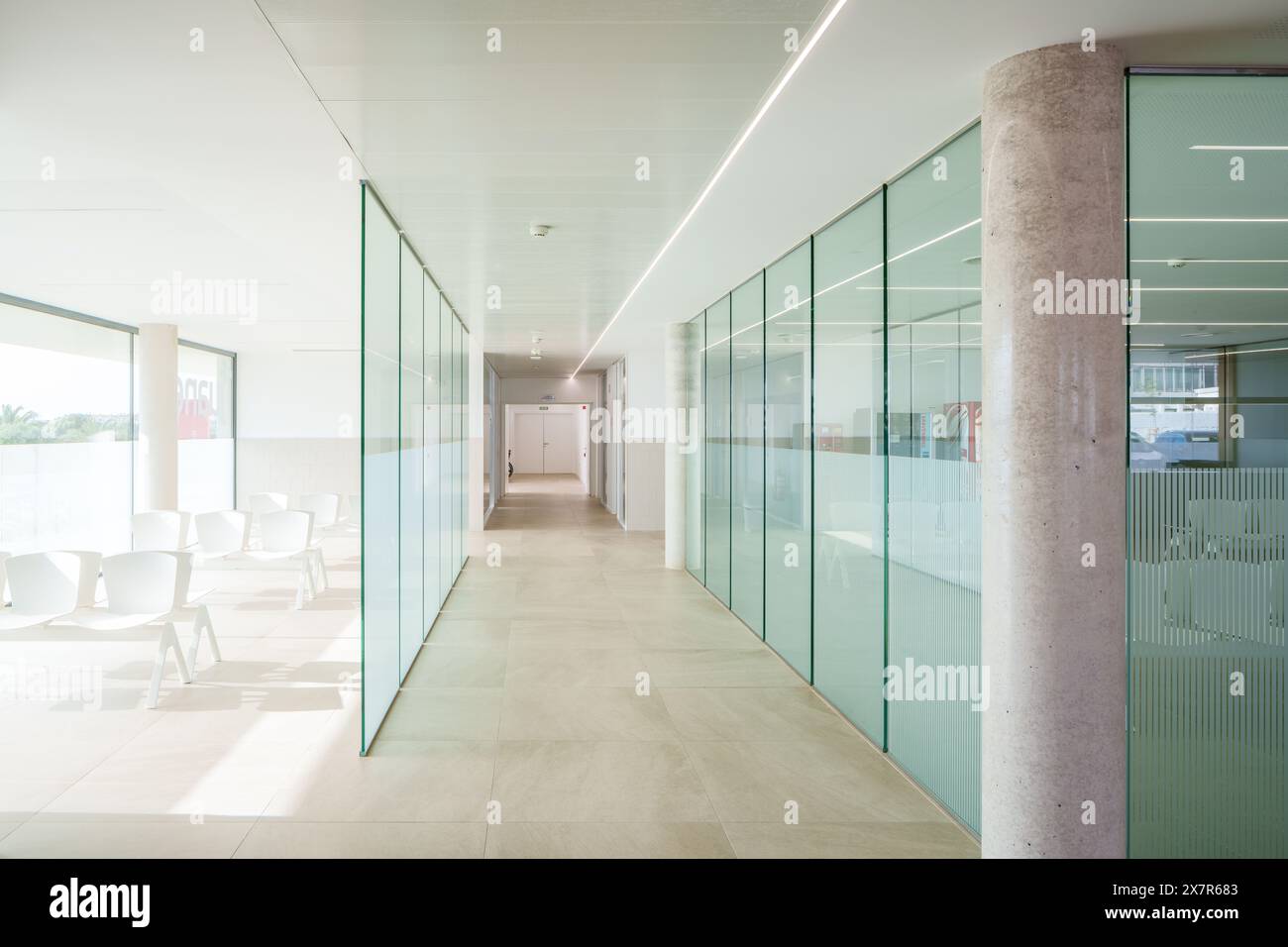 A bright and spacious hospital hallway with a clear glass partition ...