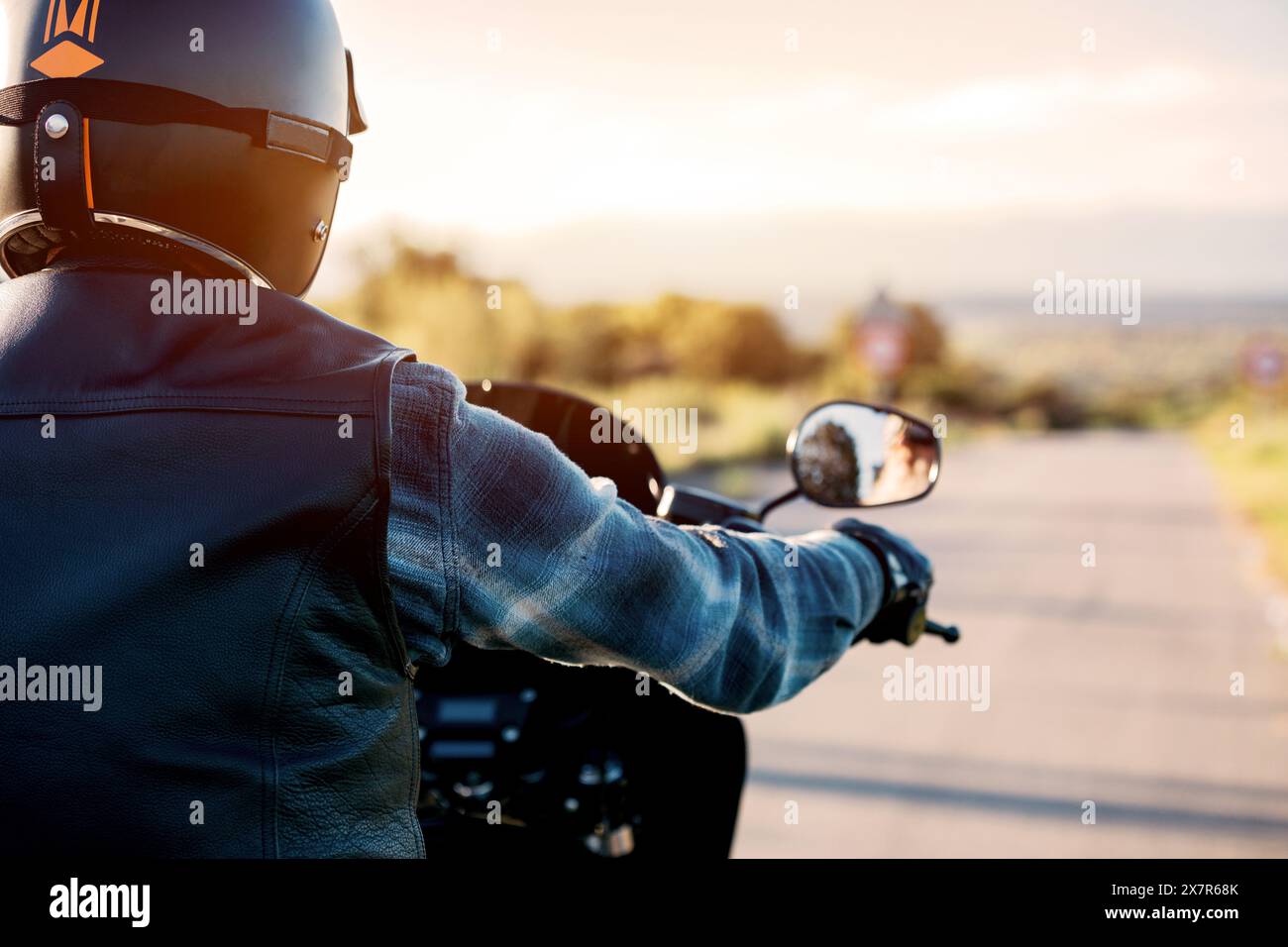 Back view of unrecognizable biker in a helmet and leather jacket enjoys ...