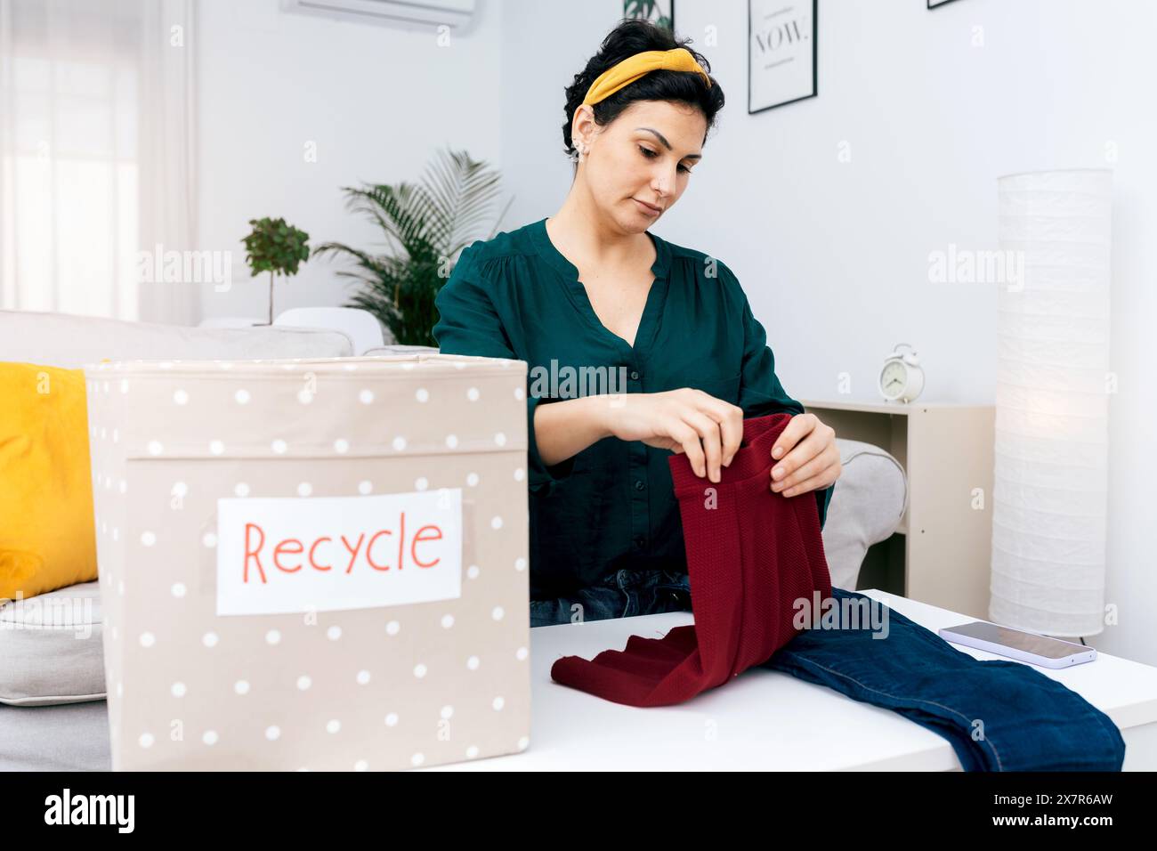 A thoughtful woman is actively engaged in sorting out clothes, choosing ...