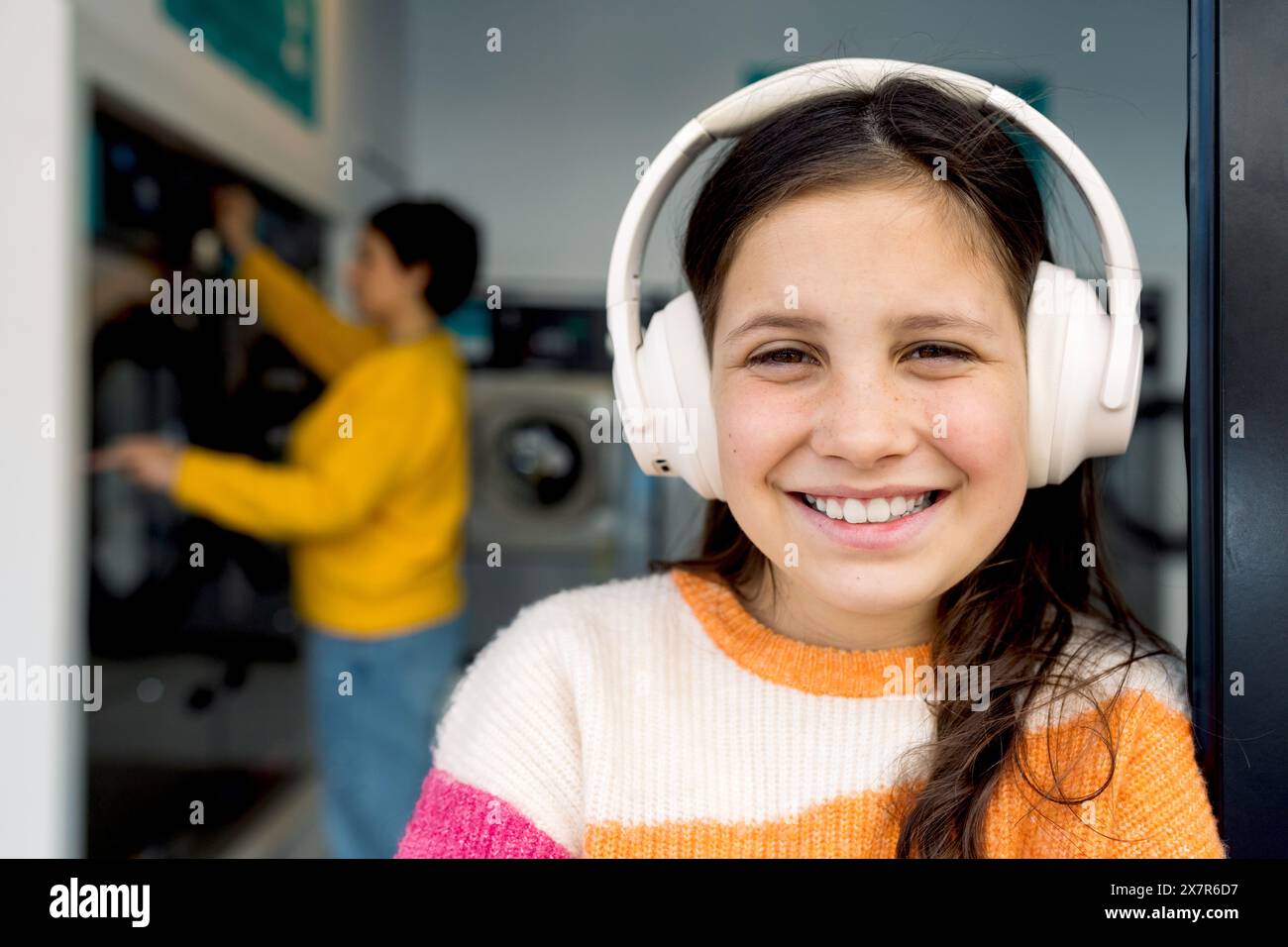 A smiling preteen girl with headphones enjoys music while a boy loads ...