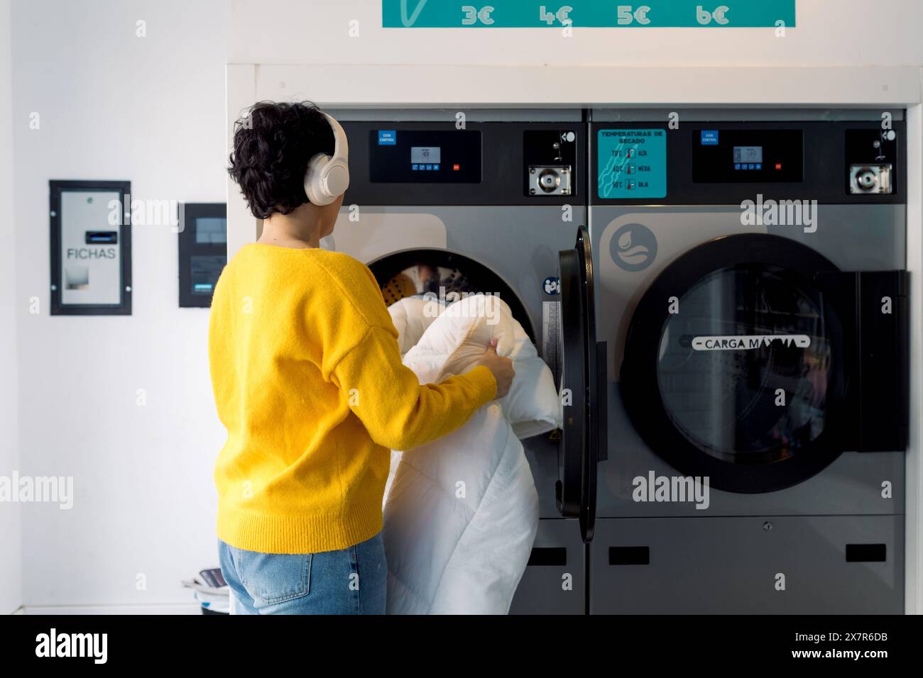 Back view of unrecognizable woman loading the laundry into a washing ...