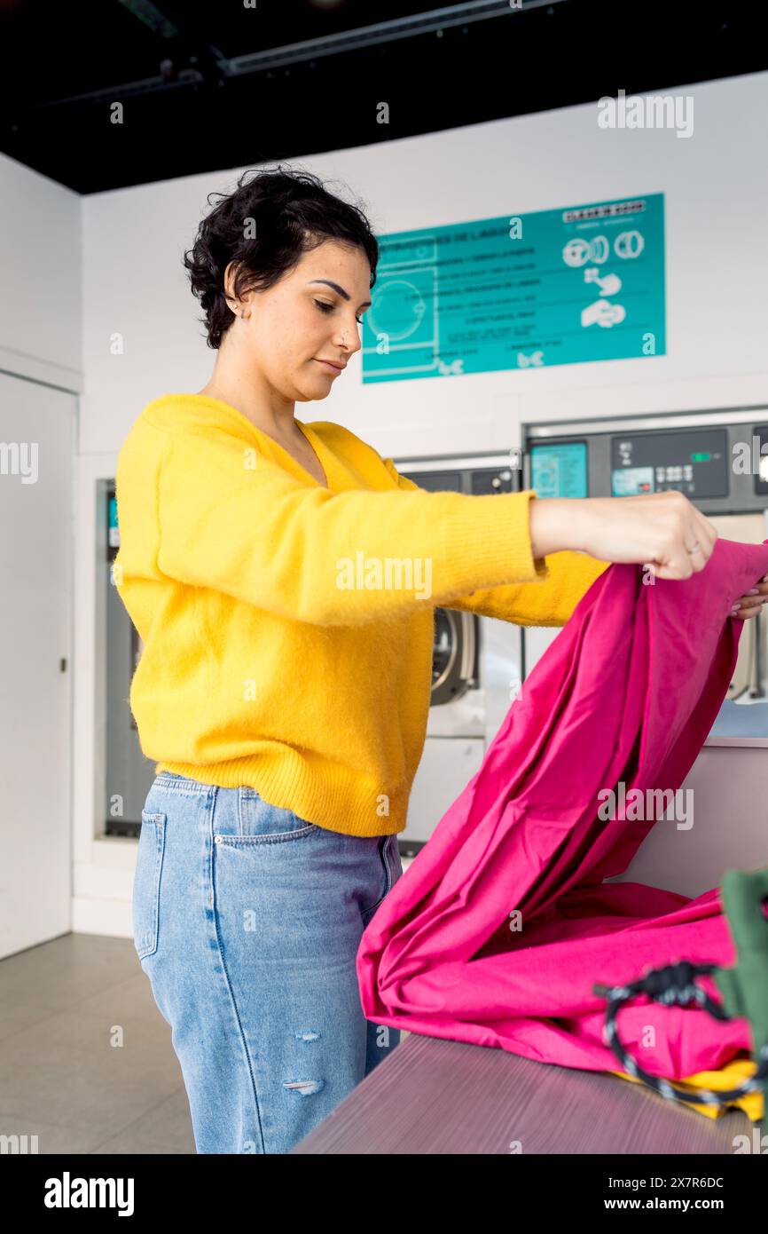 Side view of an adult woman is sorting and handling clothes in a ...