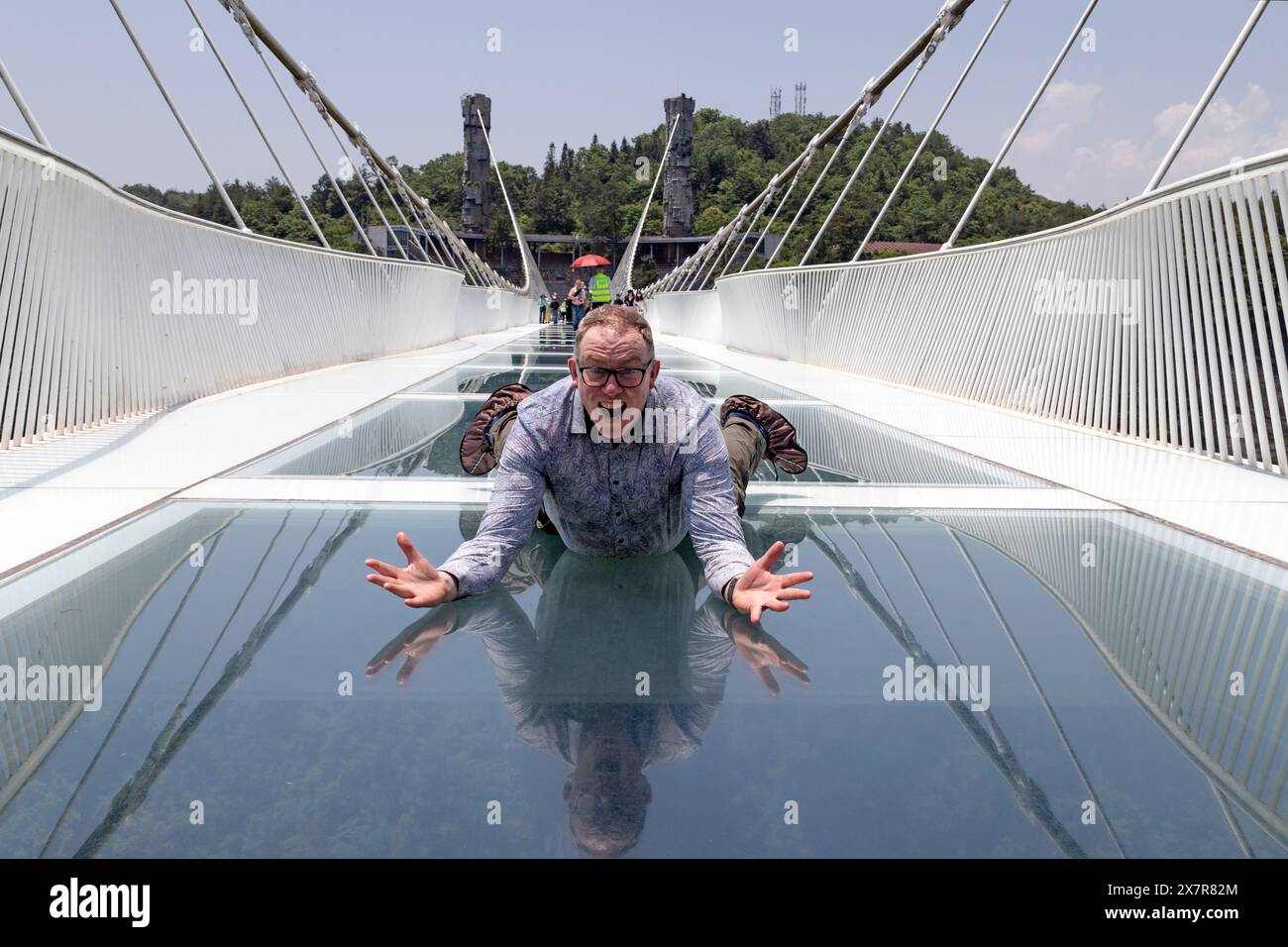 Man enjoying being on the highest glass bridge in world, over the ...