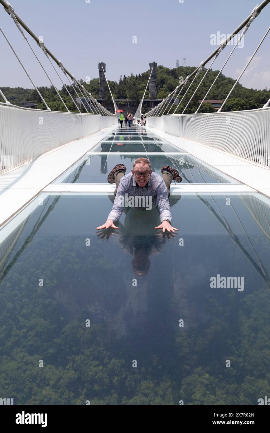 Man enjoying being on the highest glass bridge in world, over the ...