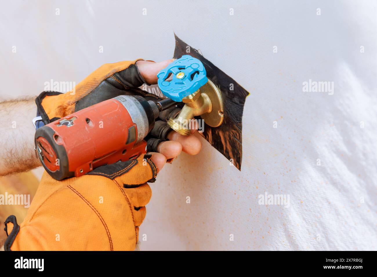 Plumber installs external water taps on house facade Stock Photo - Alamy