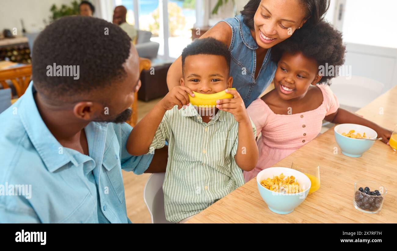 Son Having Fun Playing With Banana As Family Sit At Kitchen Counter ...