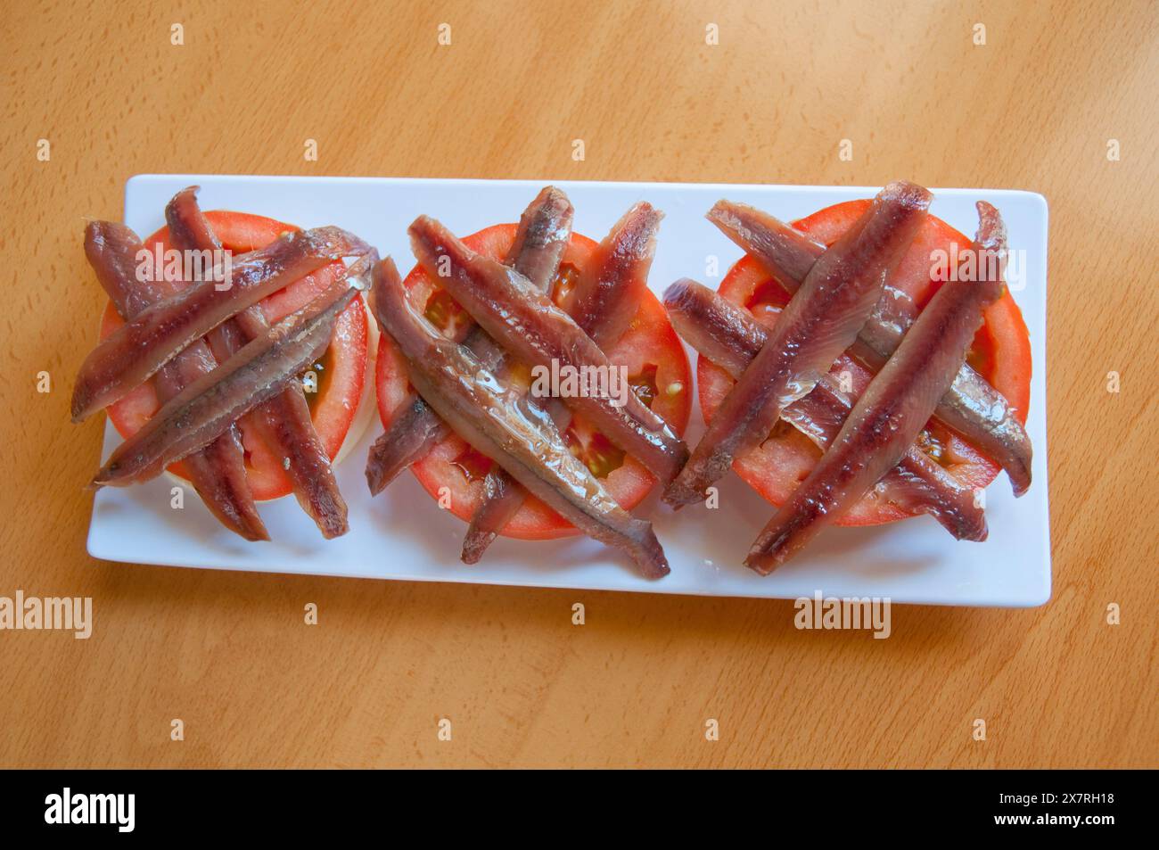Spanish tapa: anchovy fillets on sliced tomato Stock Photo - Alamy