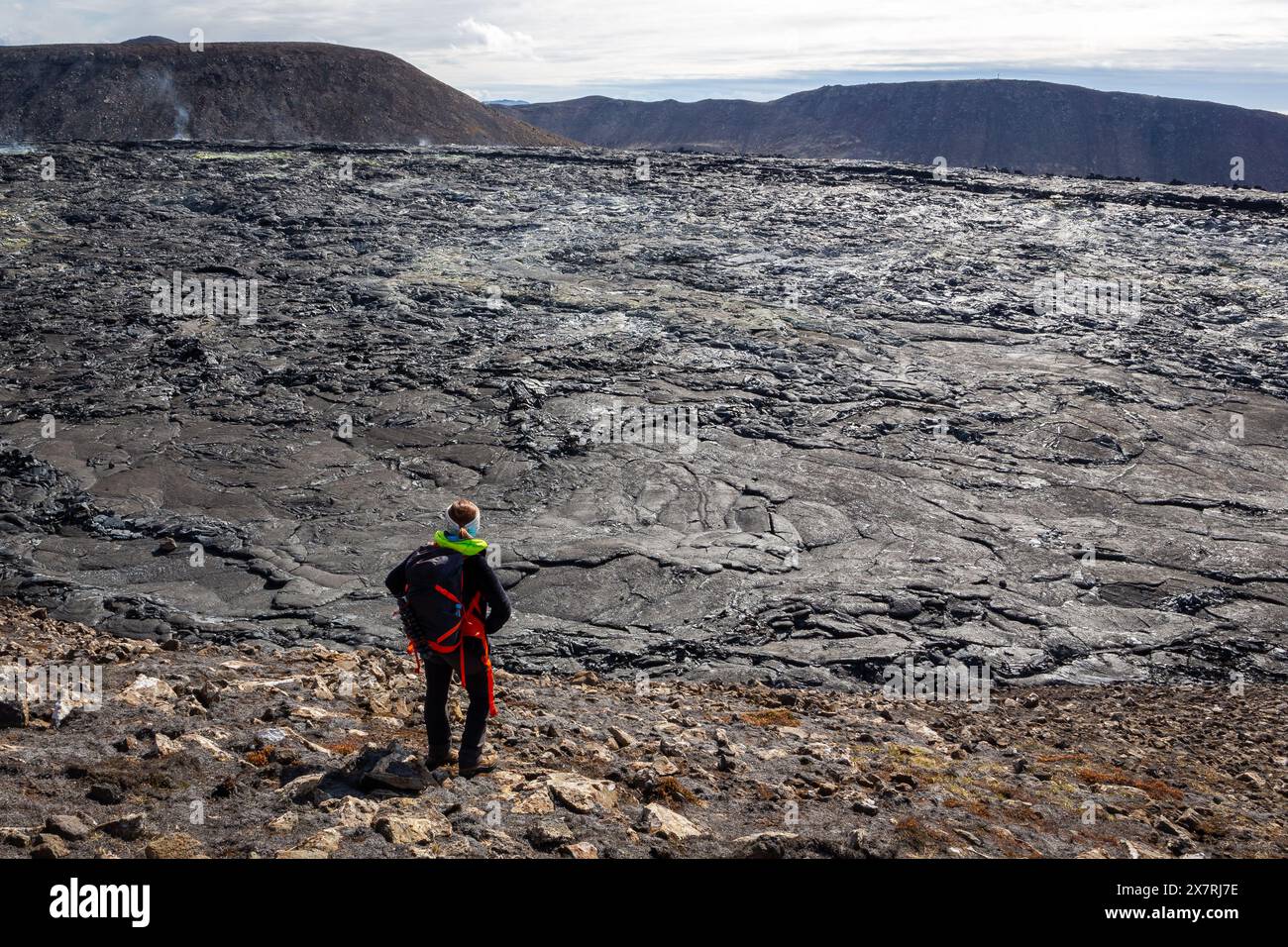 Female tourist with backpack standing on top of the molten basalt rocks ...